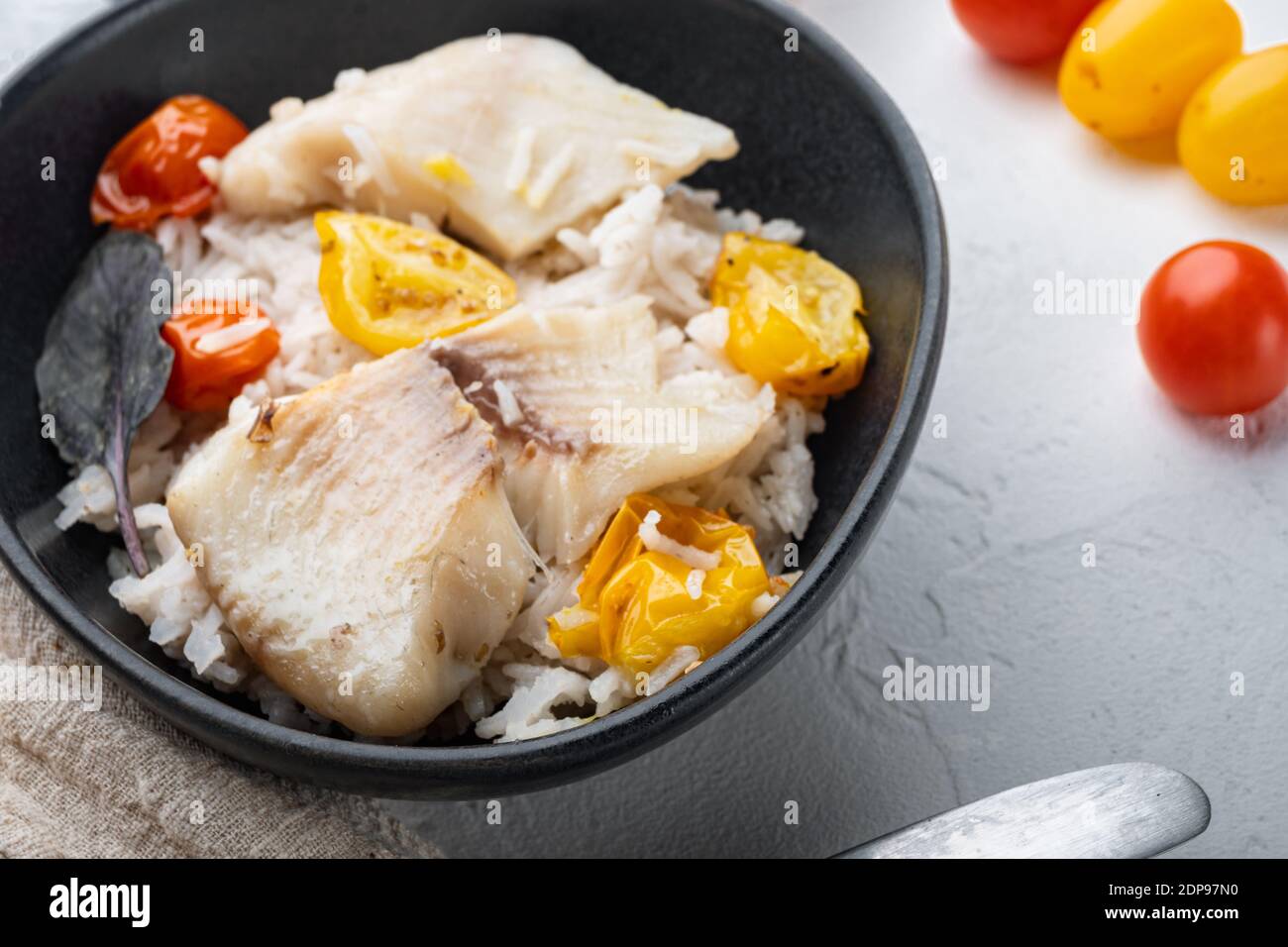 Tilapia fish with basmati rice and cherry tomatoes, in bowl, on white ...