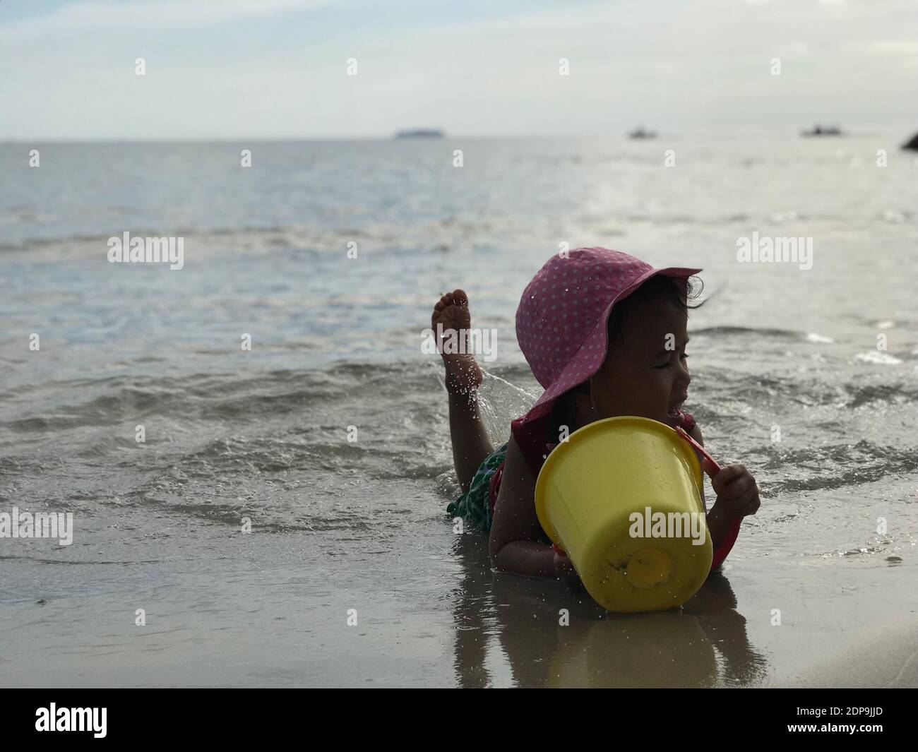 Girl Holding Bucket While Lying At Beach Stock Photo - Alamy