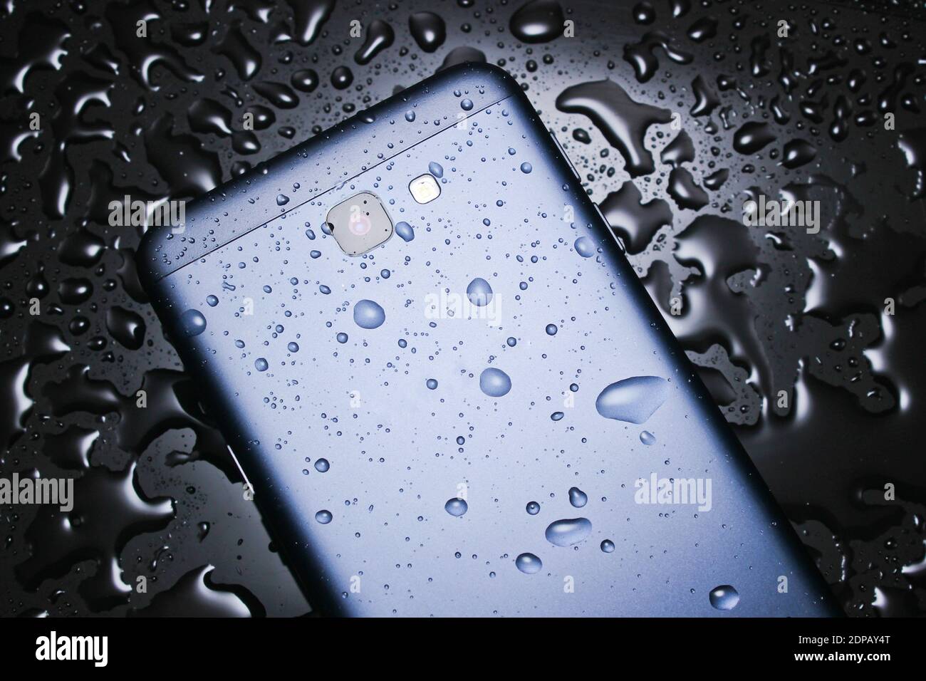 The back side of the smartphone with water drops on a black background ...