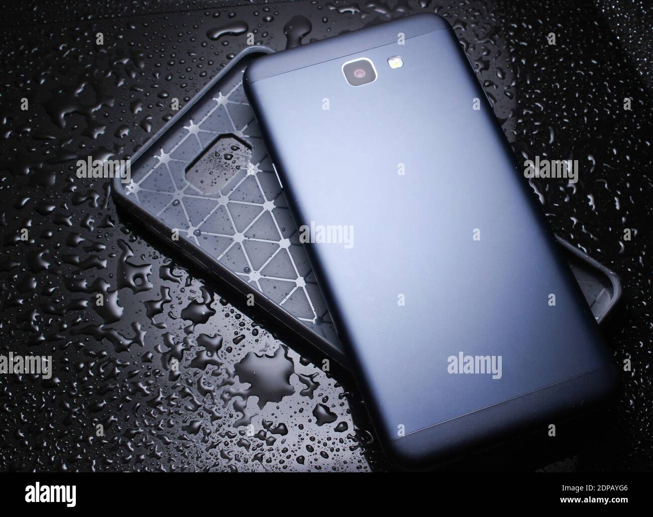 Smartphone with protective cover on black background with water drops ...