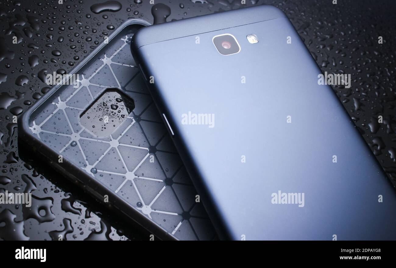 Smartphone with protective cover on black background with water drops ...