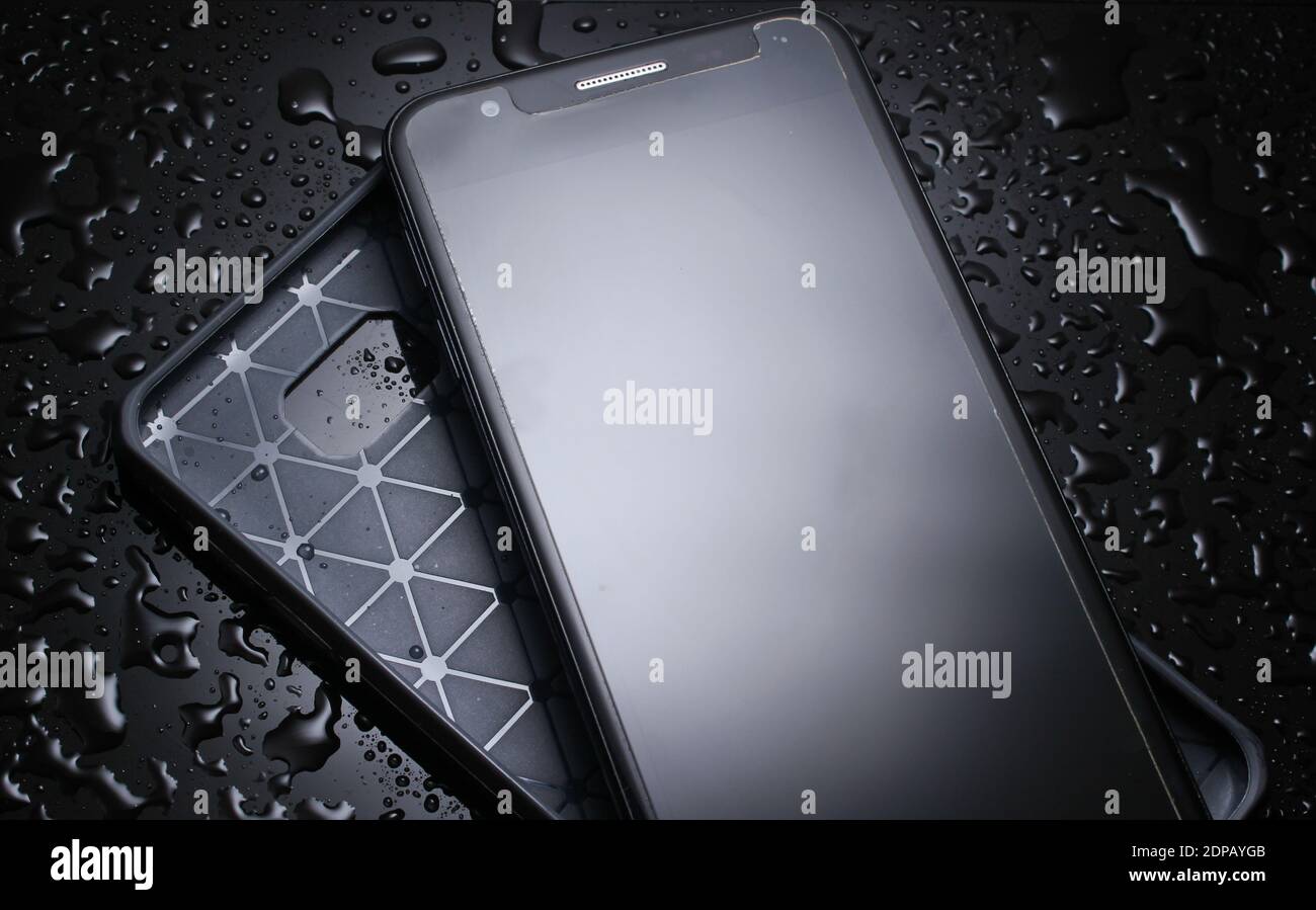 Smartphone with protective cover on black background with water drops ...