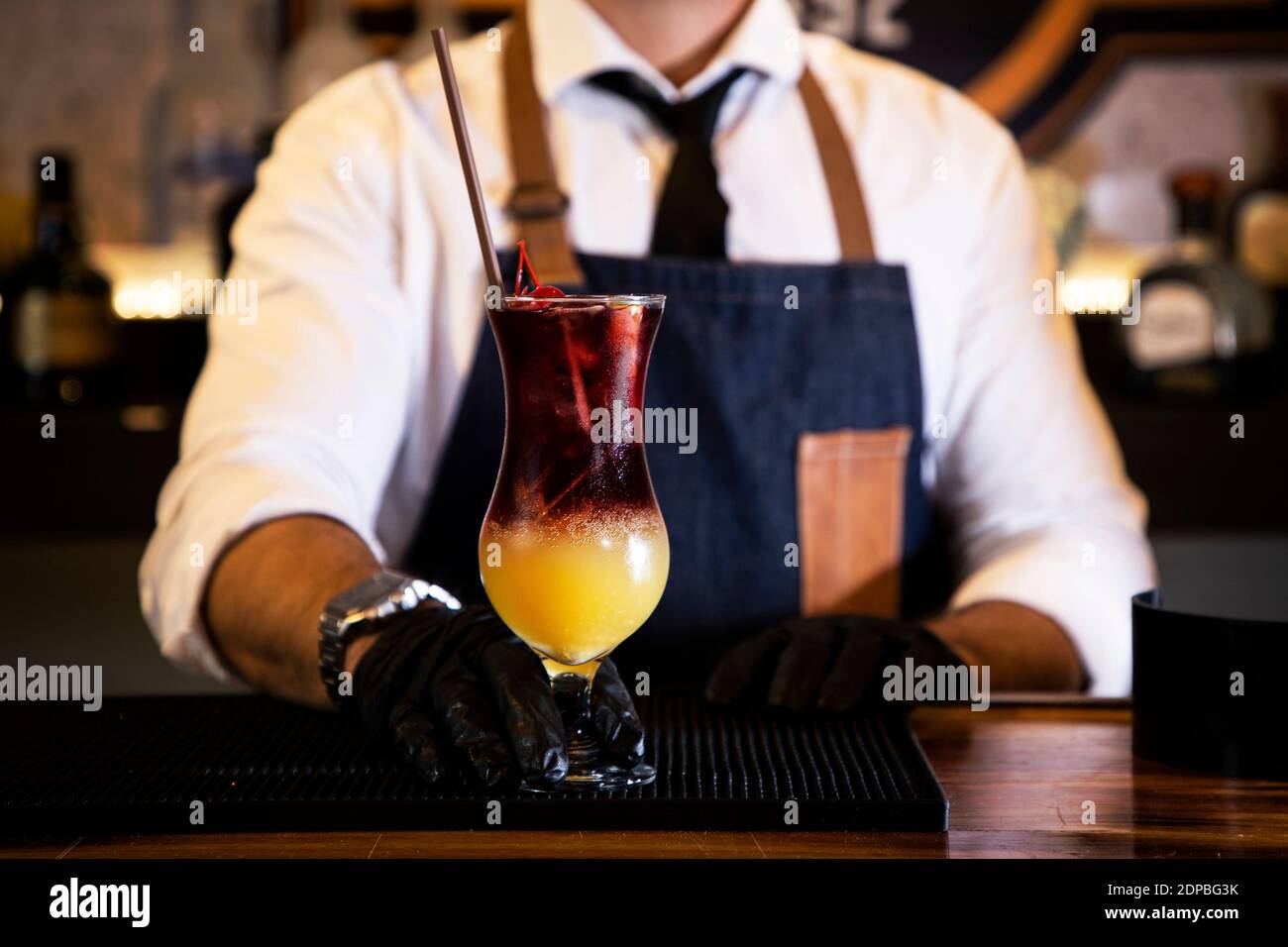 Detail of the hands of a bartender with black gloves placing a crystal ...