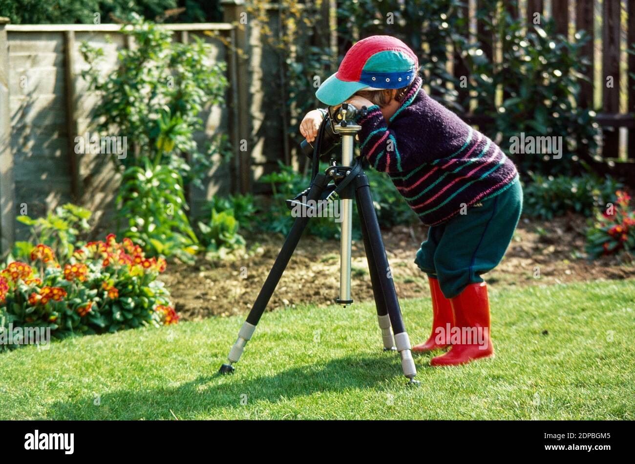 Child looking through camera on a tripod Stock Photo - Alamy