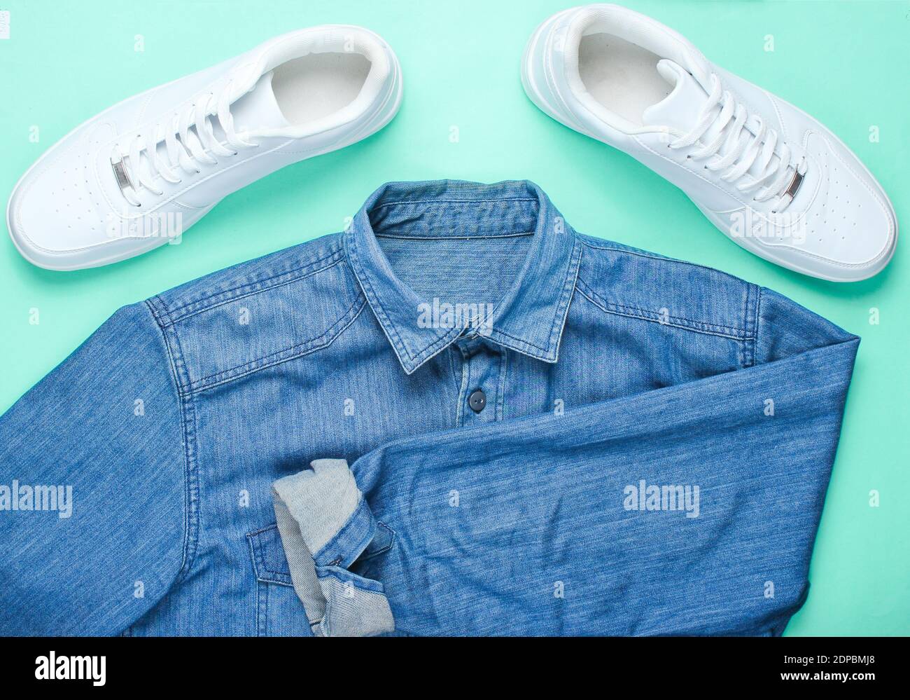 Flat lay style white hipster sneakers and denim shirt on mint-colored ...