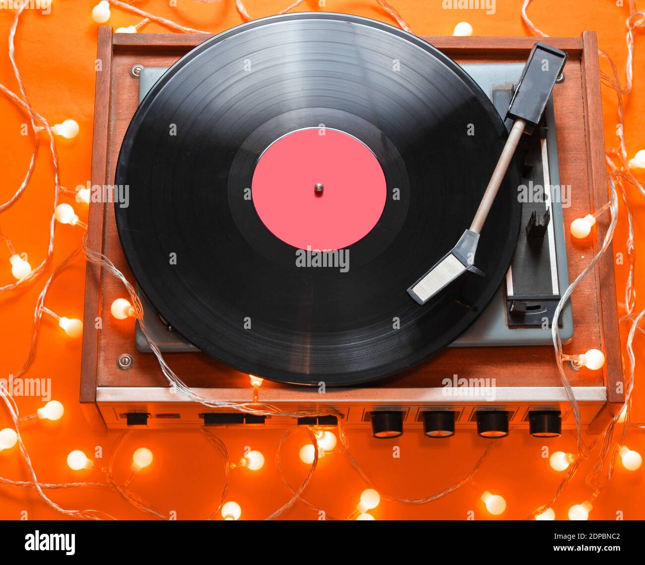 Retro 80s vinyl player with bright glowing garlands on orange ...