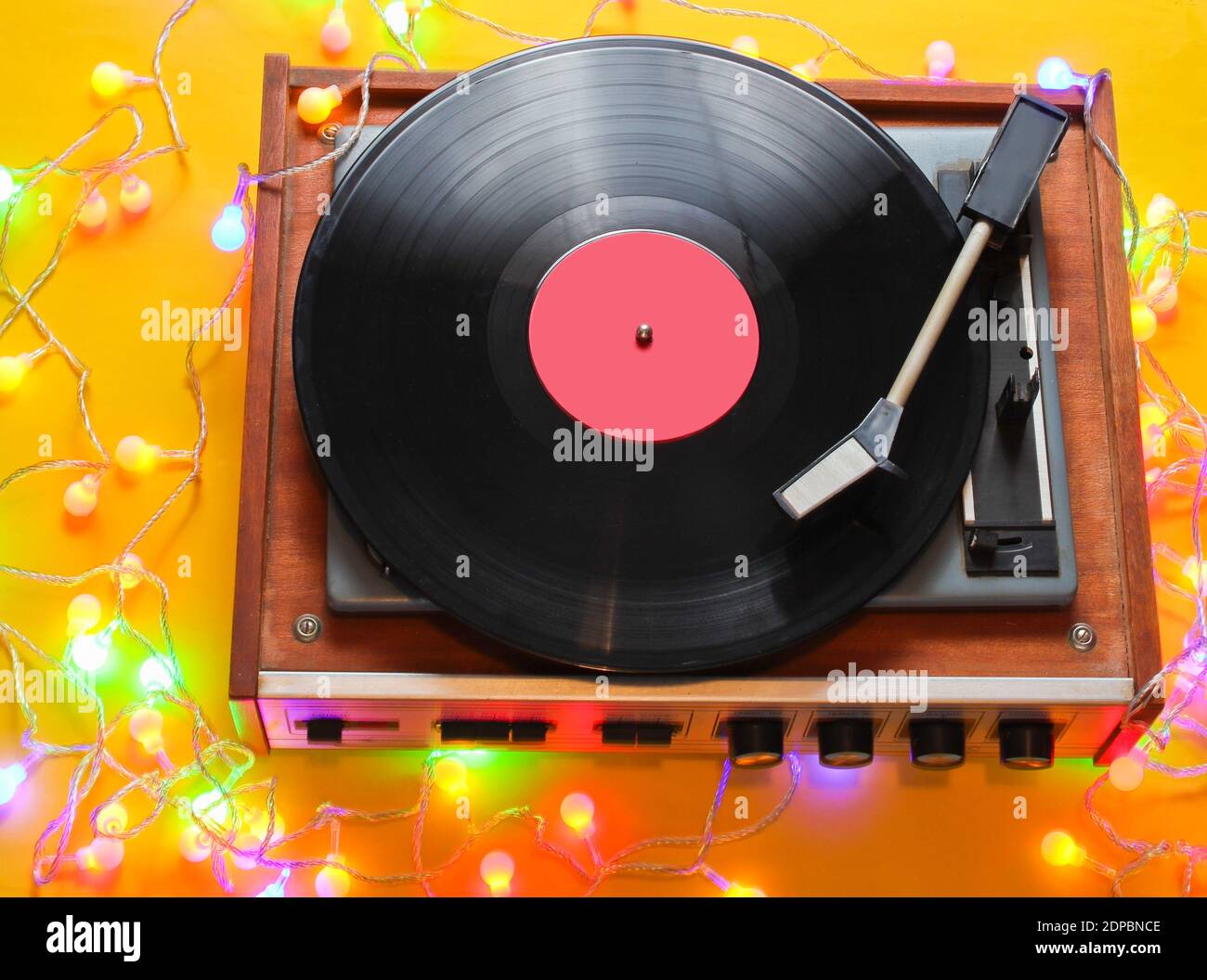 Retro 80s vinyl player with bright glowing garlands on a yellow ...