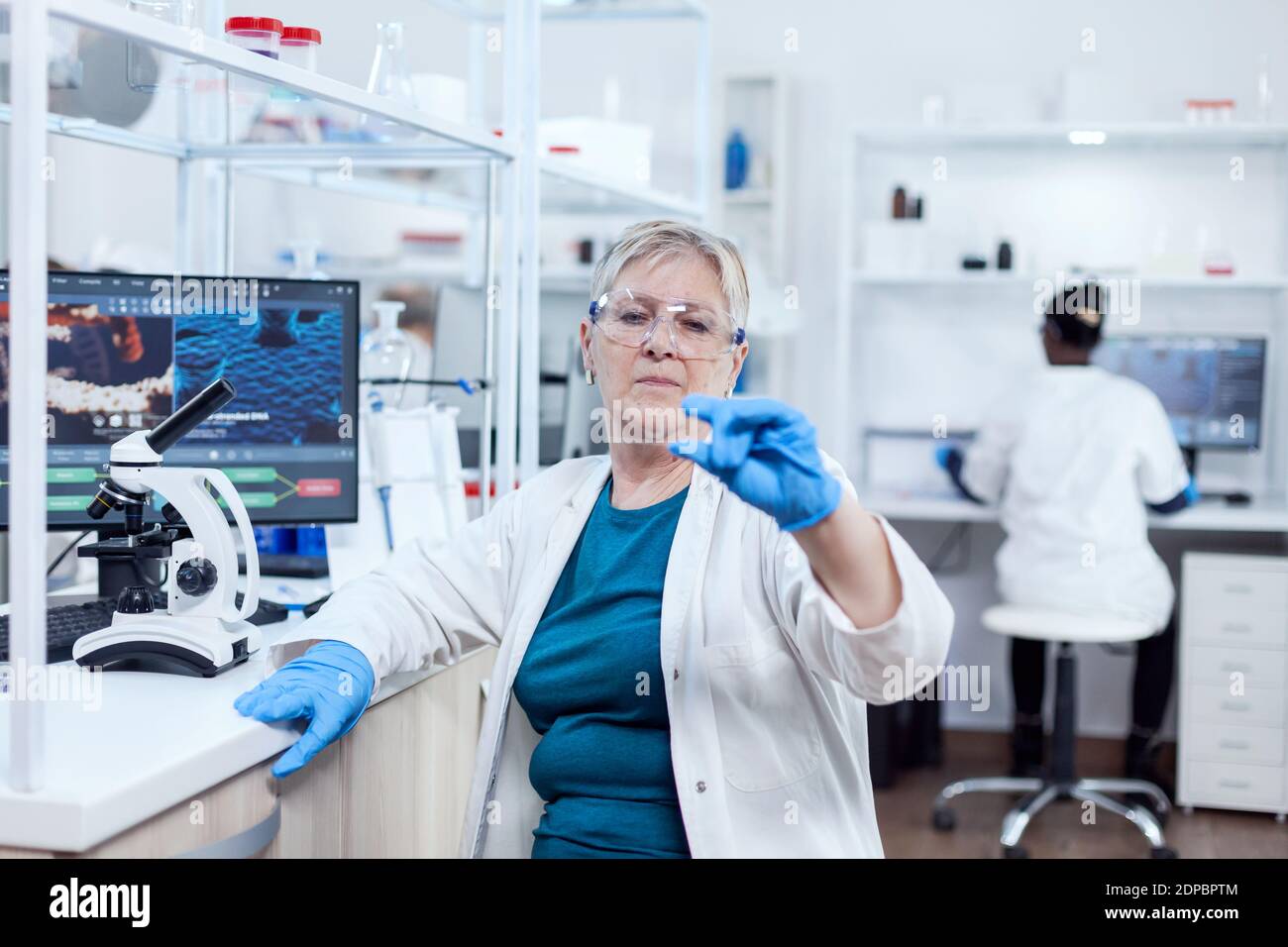 Senior scientist in modern laboratory holding genetic sample on ...