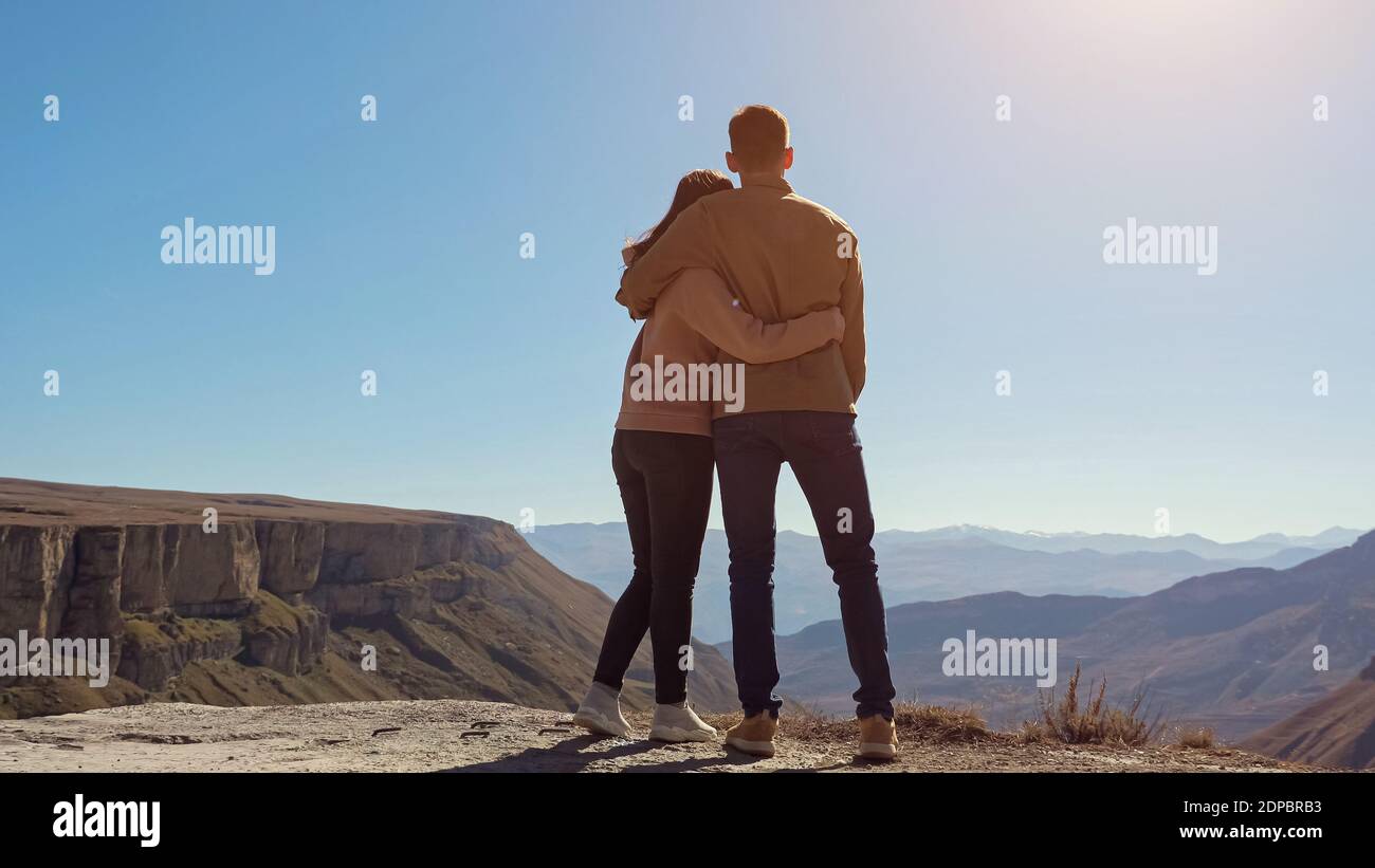 Young couple in love over the cliff admire the view of the valley on a ...