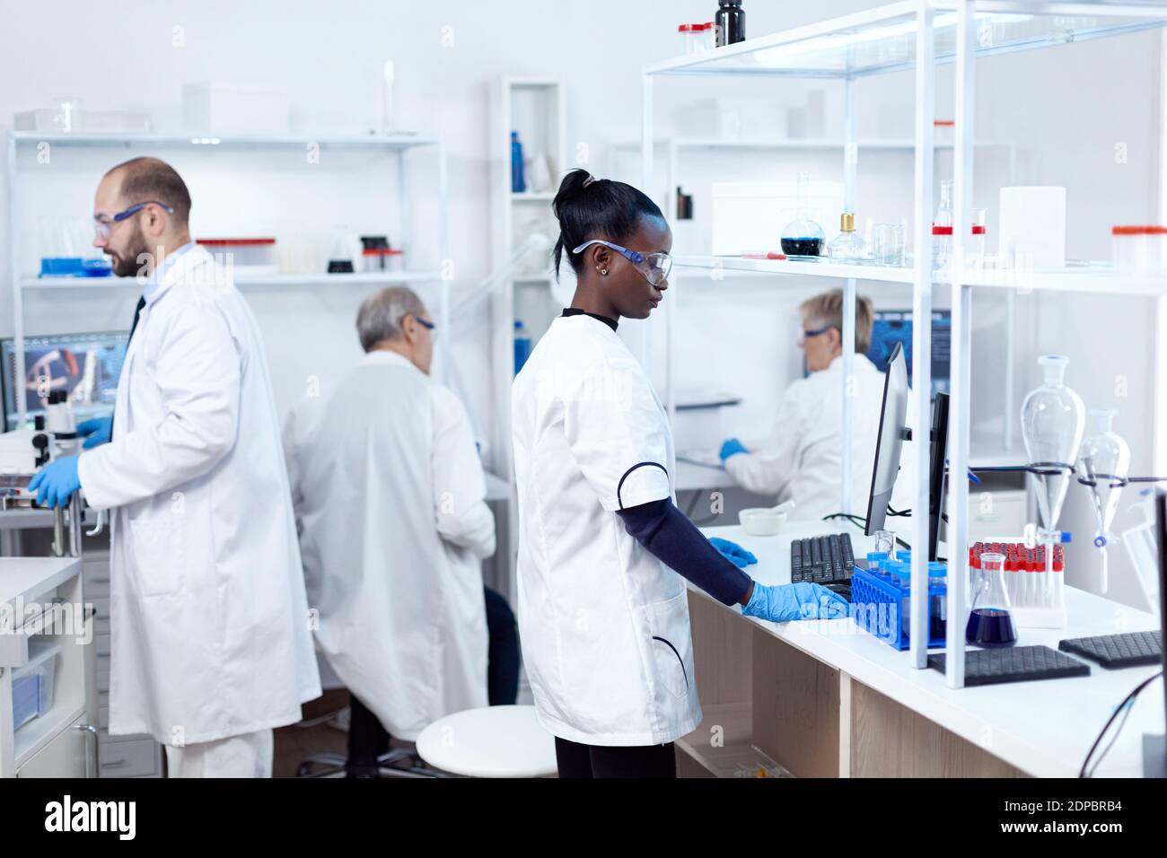 African scientist and her colleagues doing experiments in sterile ...