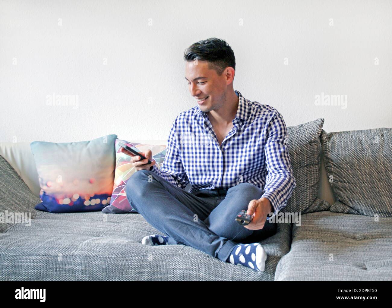 Full Length Of Man Using Phone While Watching Tv On Sofa At Home Stock ...