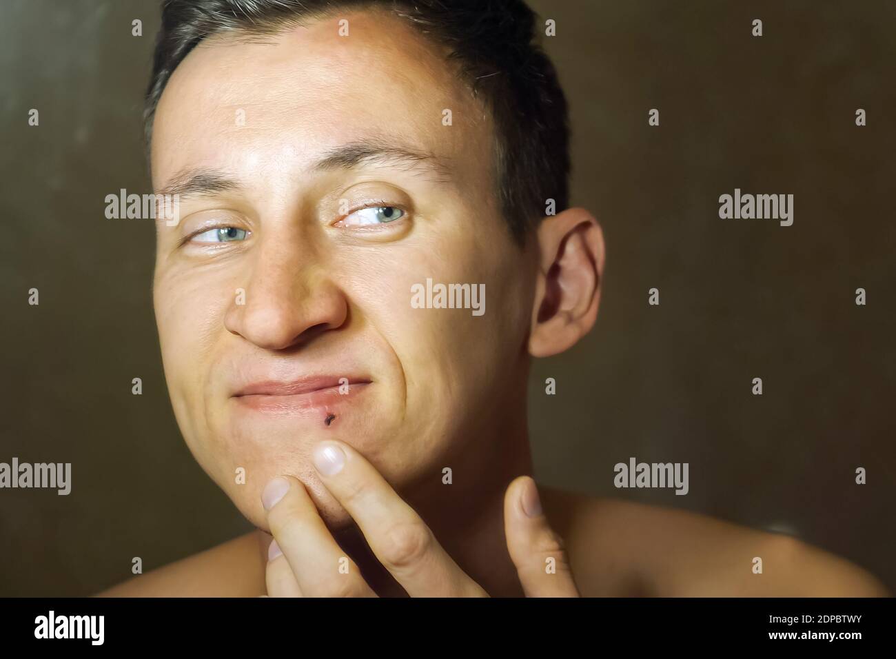 Man with grey eyes looks carefully at mirror reflection of face and ...