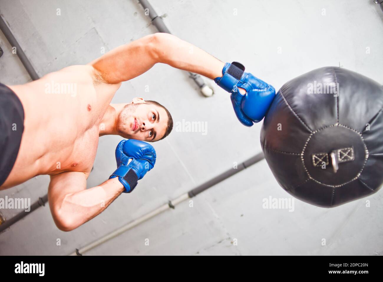 Handsome sports man boxer trains hand punches with a punching bag ...