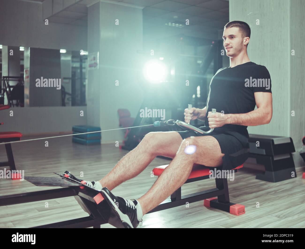 Man is training with equipment rowing training machine by pulling ...