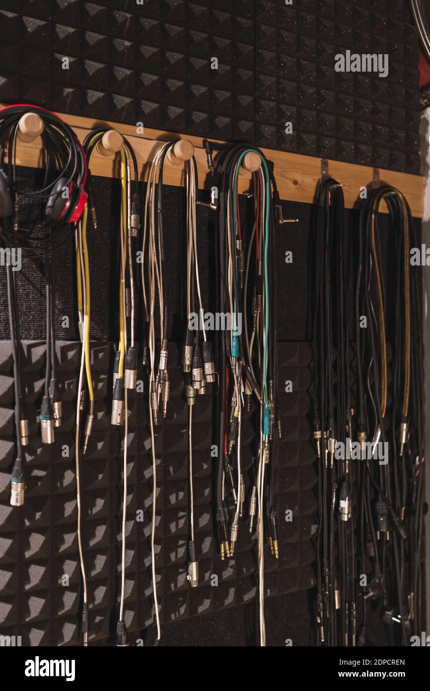 A vertical shot of audio cables and headphones hanging on the wall in ...