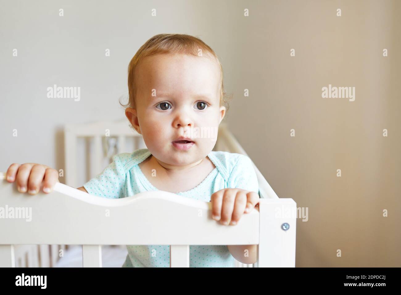 Little child standing in baby crib, lovely kid looking out the little ...