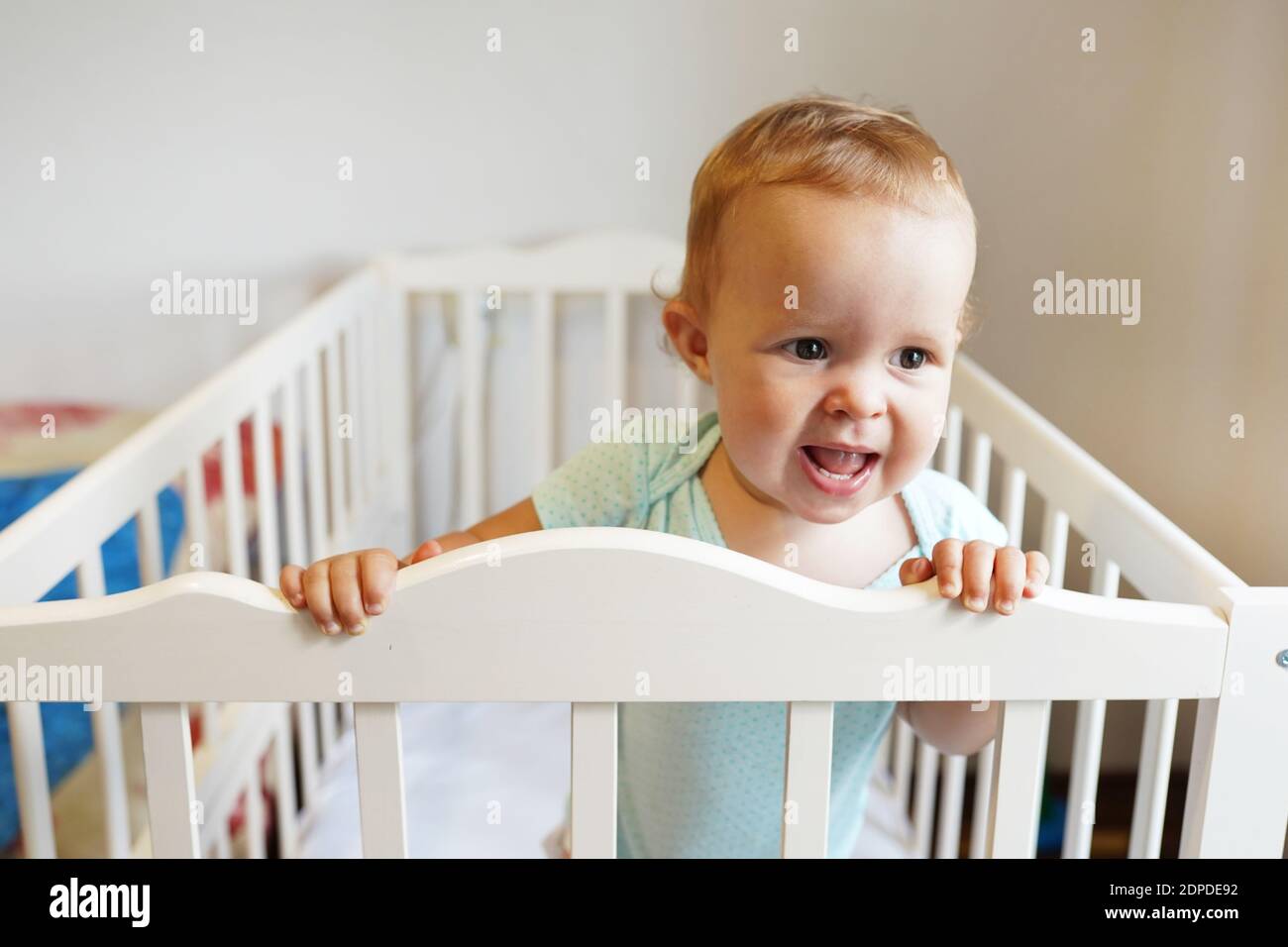 Beautiful baby standing in crib. Portrait of cute baby girl stand in ...