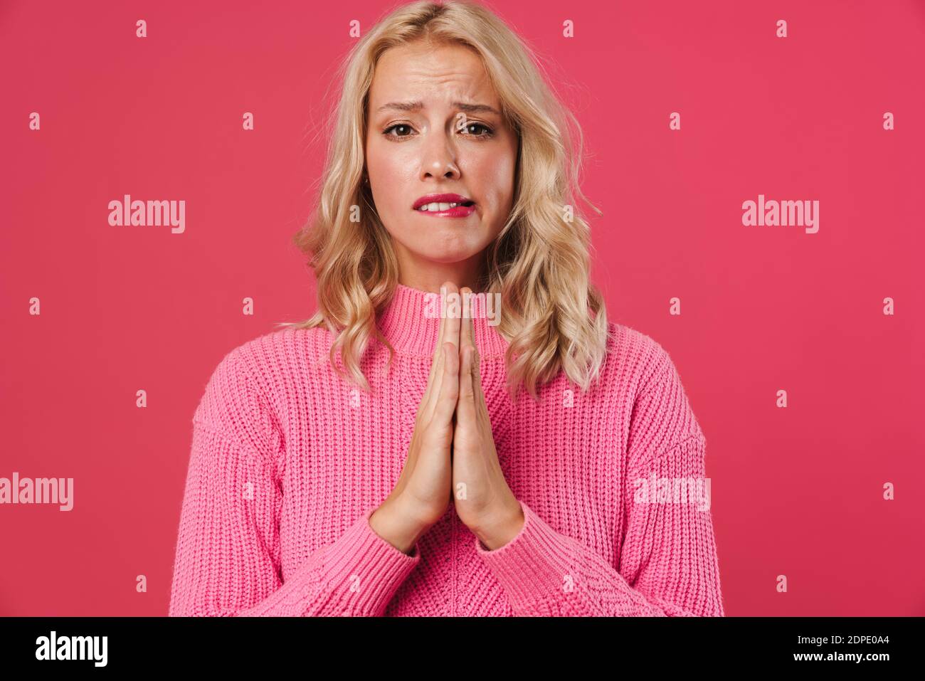 Worried young woman asking for something isolated over pink background ...