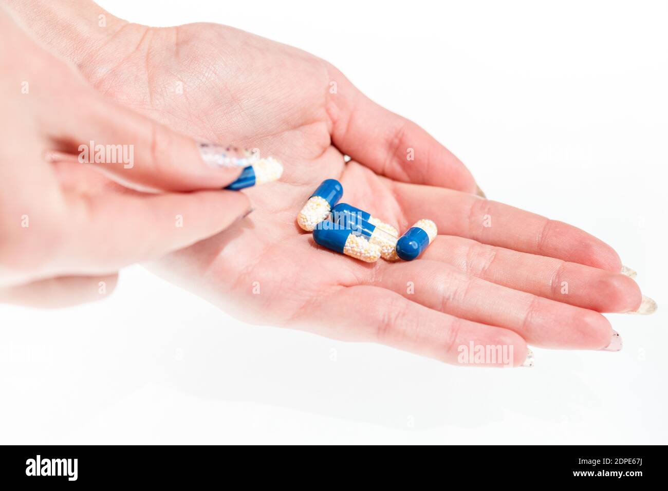 Close-up Of Hands Holding Capsules Over White Background Stock Photo ...
