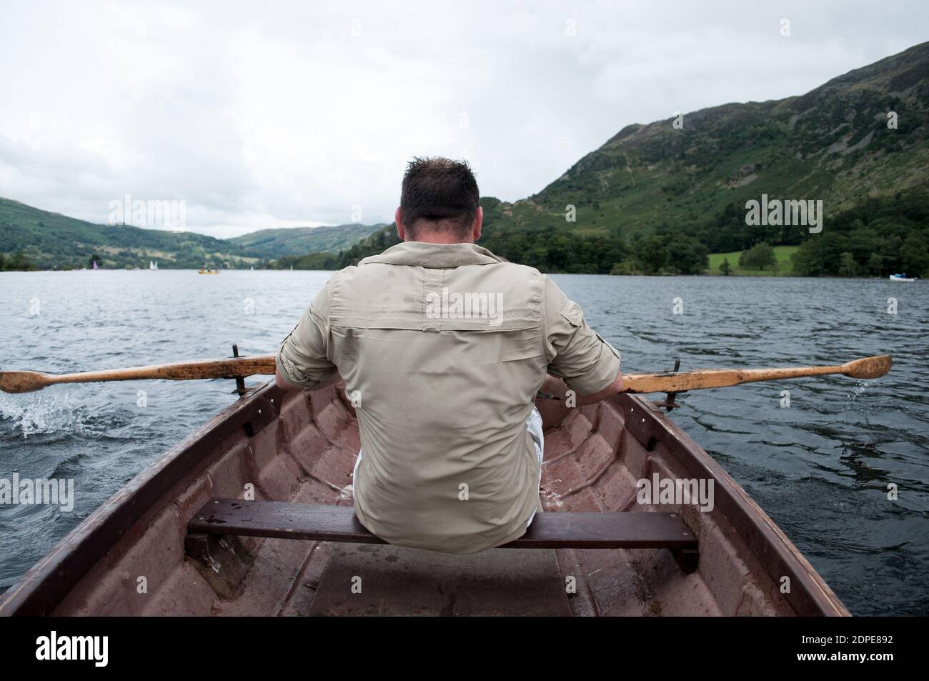 Man rowing a small boat across a lake Stock Photo - Alamy