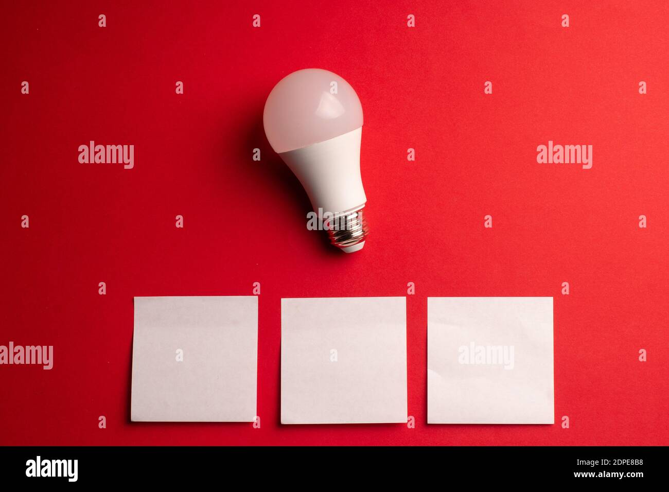 A top view of an electric light bulb with white papers on a red ...