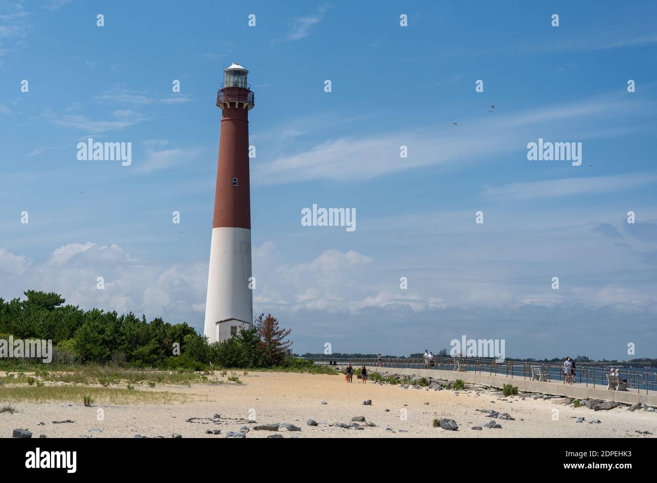 The Barnegat Lighthouse on the shore of the sea against the cloudy sky ...
