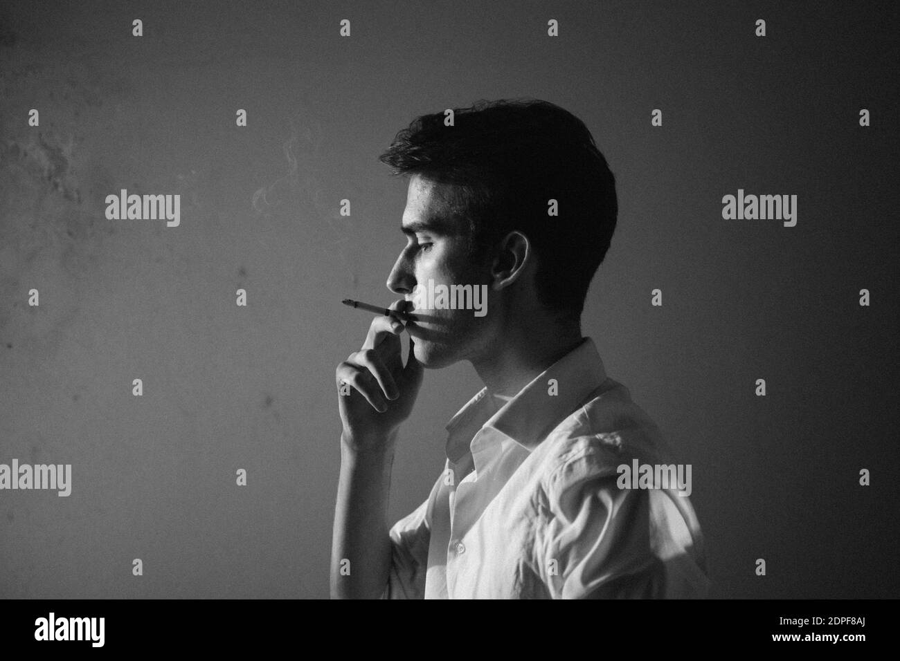 Side View Of Young Man Smoking Cigarette Against Gray Background Stock ...