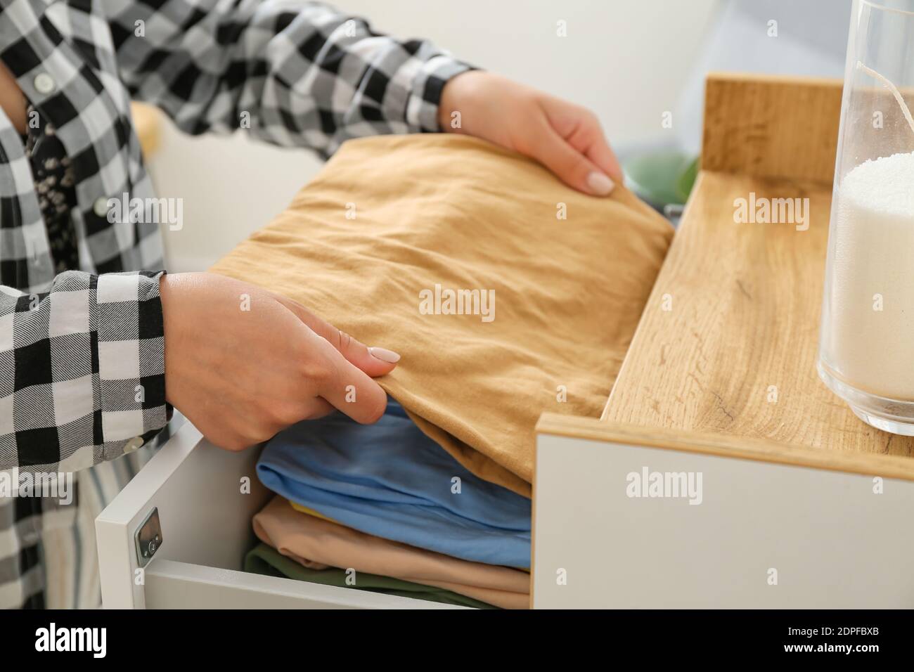 Woman folding clothes in chest of drawers Stock Photo - Alamy
