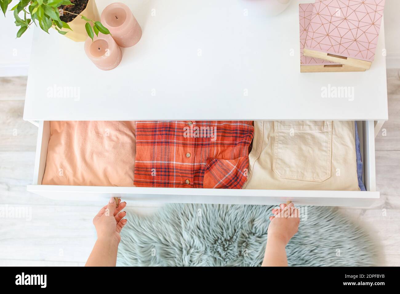 Woman folding clothes in chest of drawers Stock Photo - Alamy