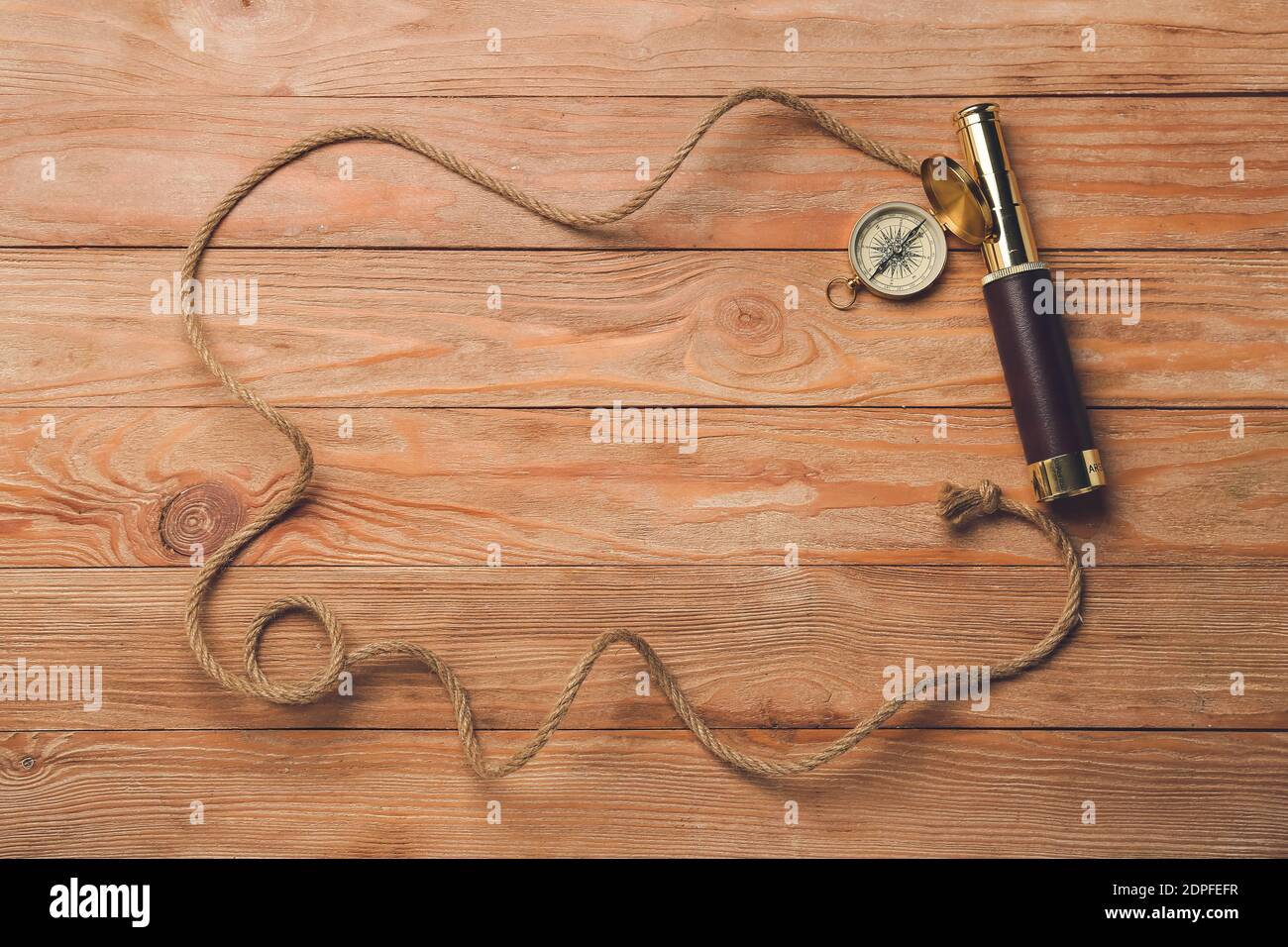 Frame made of rope, spyglass and vintage compass on wooden background ...