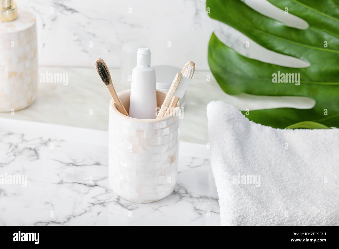 Holder with wooden toothbrushes and toothpaste on table in bathroom ...
