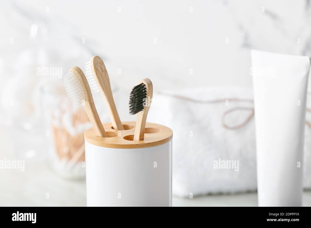 Holder with wooden toothbrushes and toothpaste on table in bathroom ...