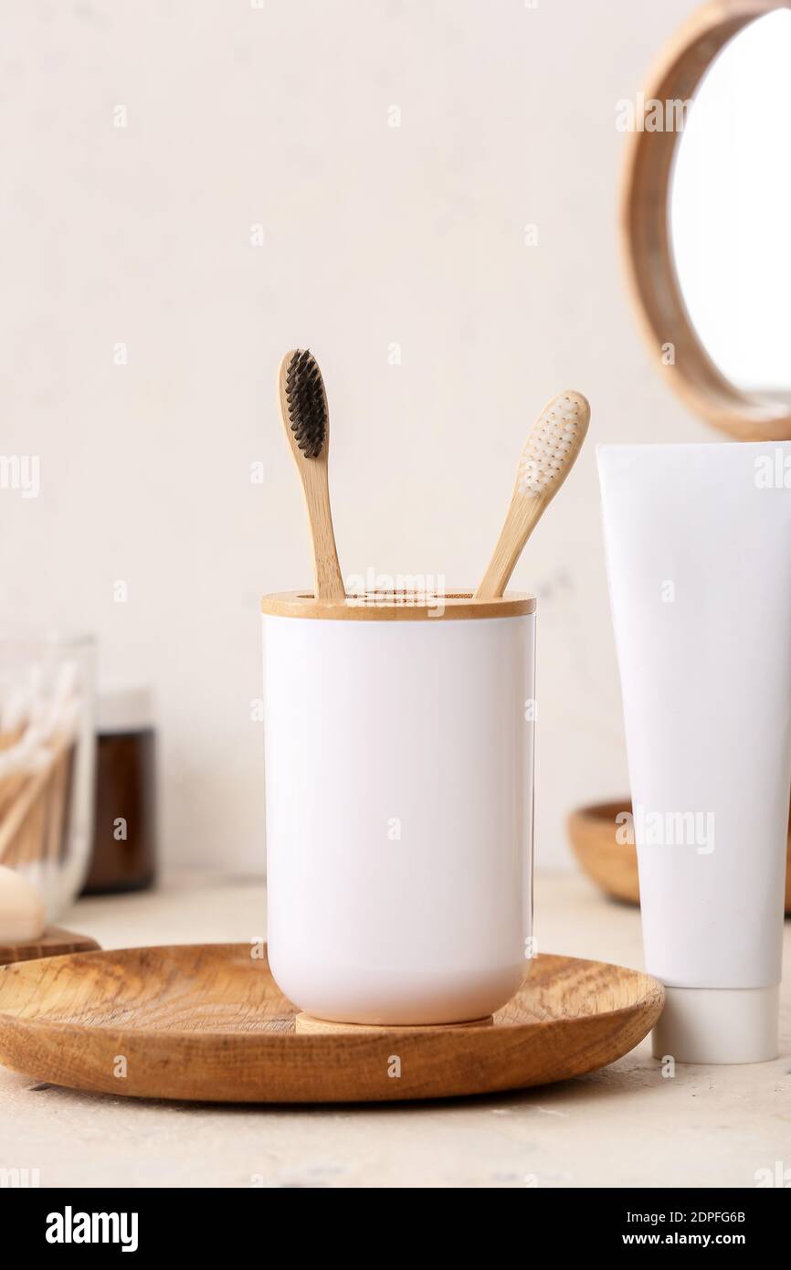 Holder with wooden toothbrushes and toothpaste on table in bathroom ...