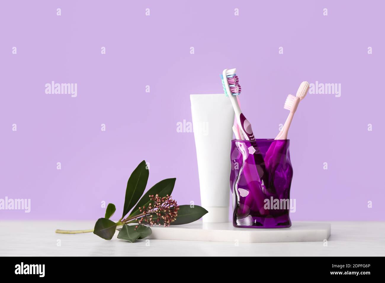 Holder with toothbrushes and toothpaste on table Stock Photo - Alamy