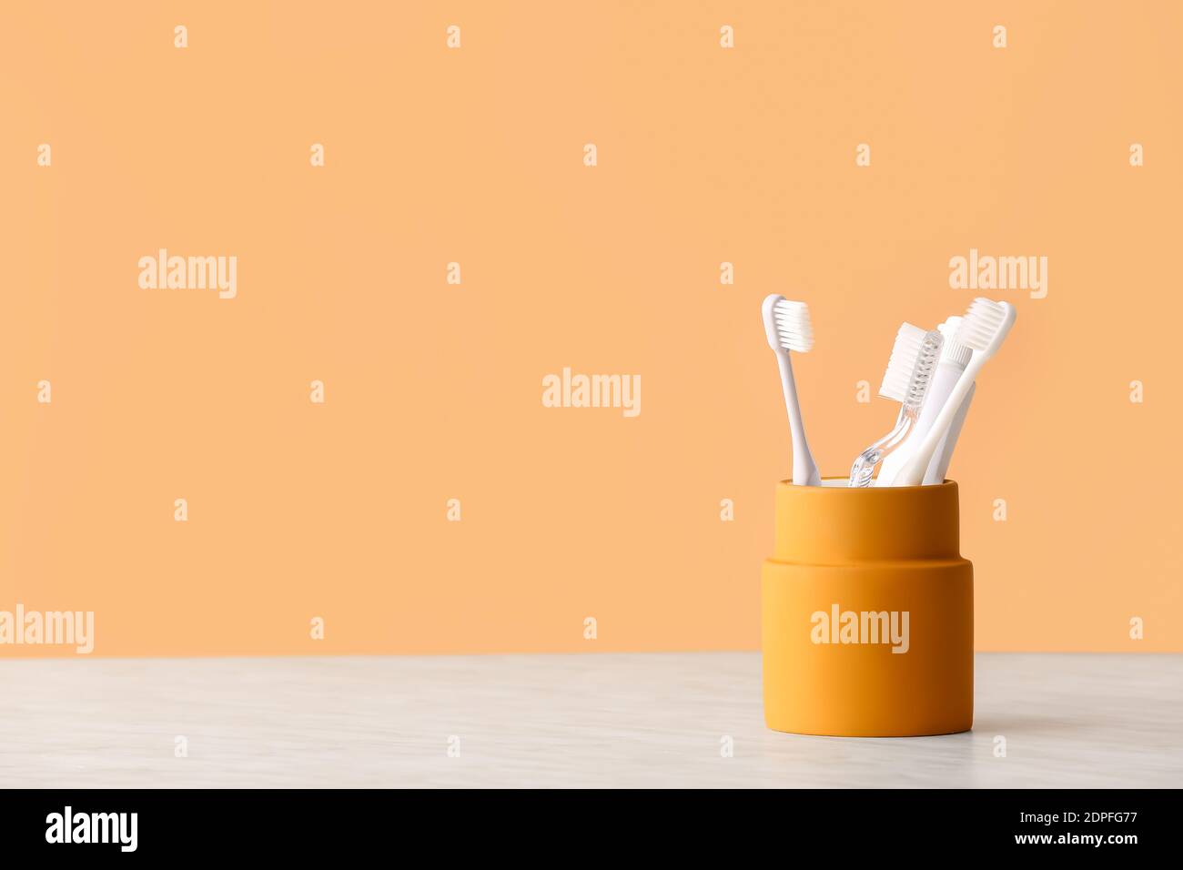 Holder with toothbrushes and toothpaste on table Stock Photo - Alamy