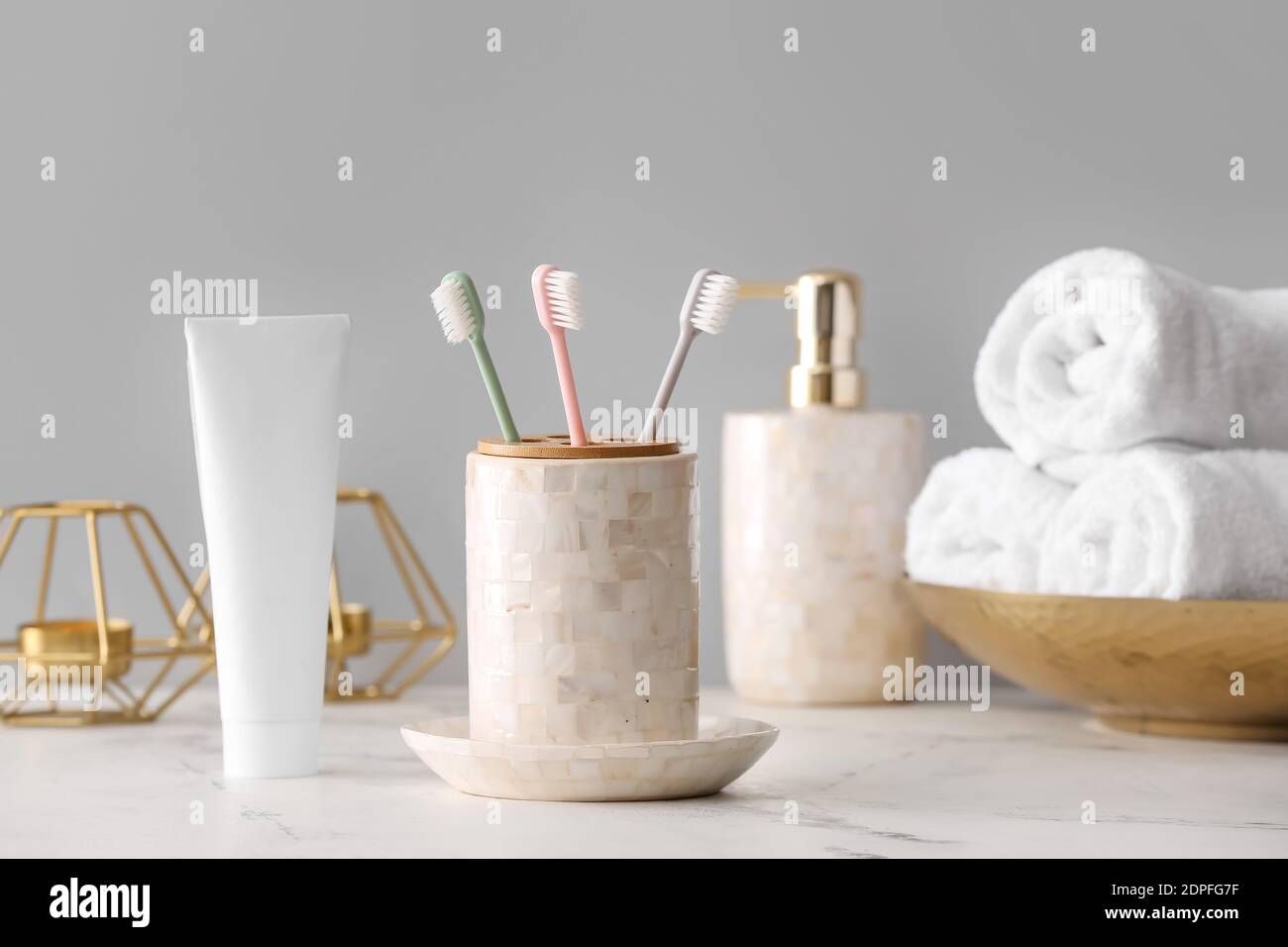 Holder with toothbrushes and toothpaste on table in bathroom Stock ...