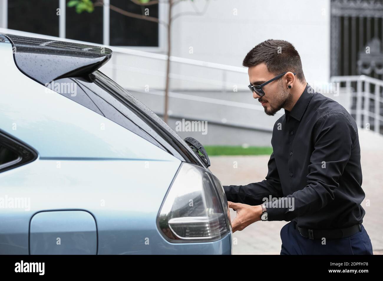 Handsome man opening trunk of modern car Stock Photo - Alamy