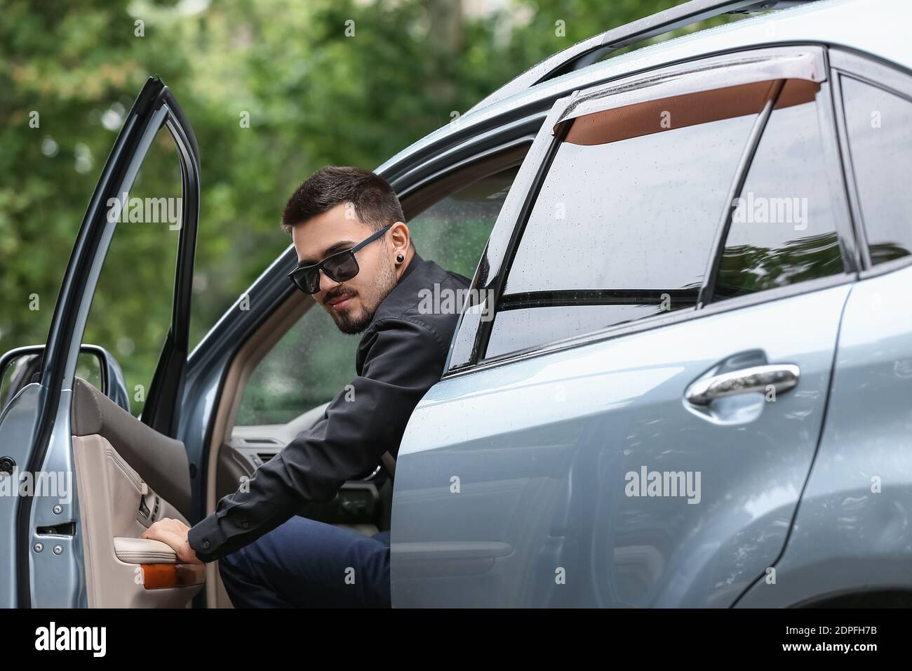 Handsome man getting out of modern car Stock Photo - Alamy