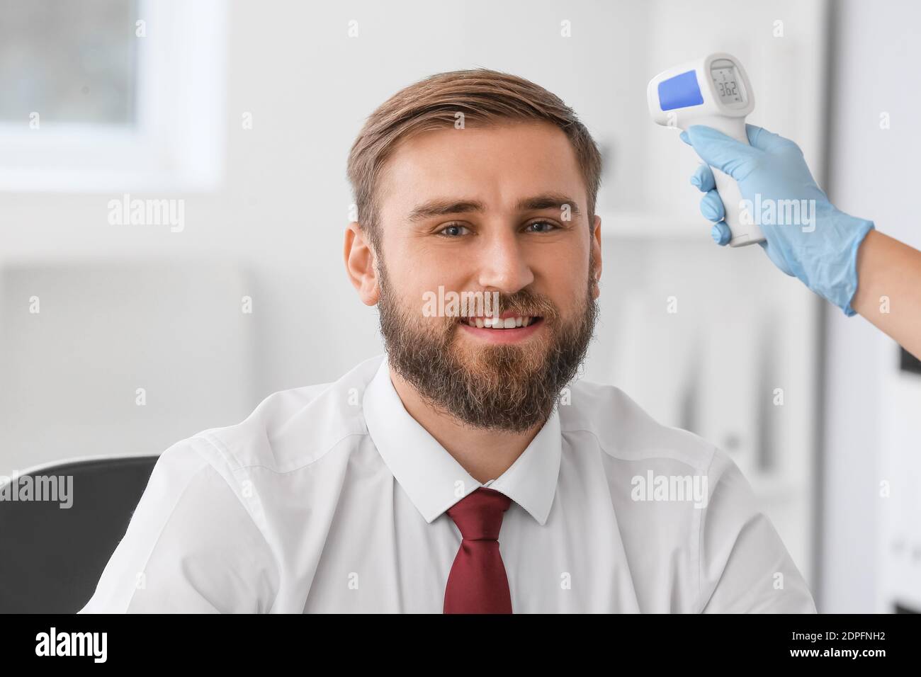 Measuring of man's temperature in office. Coronavirus epidemic Stock ...