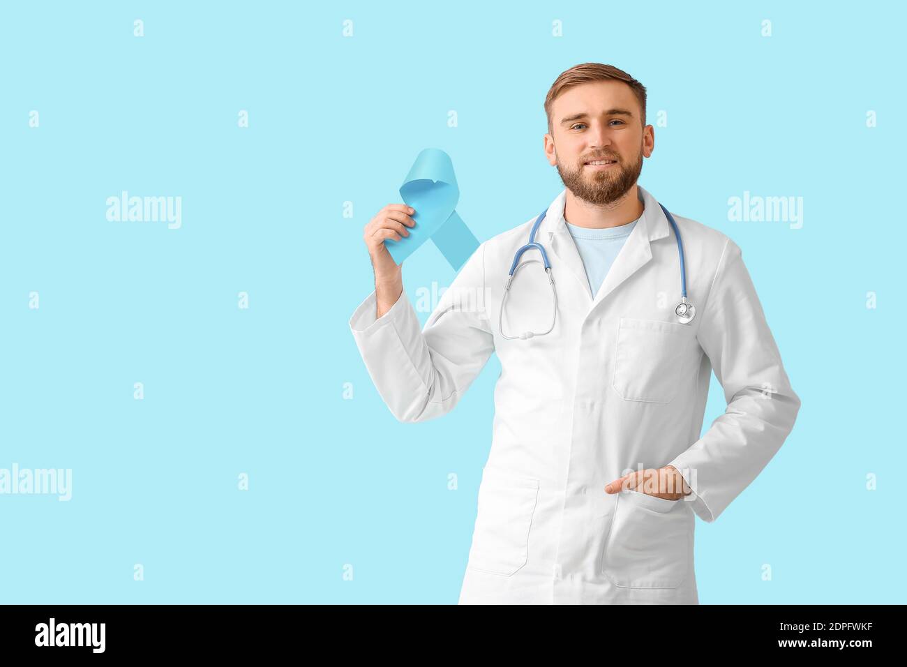 Doctor with blue ribbon on color background. Prostate cancer awareness ...