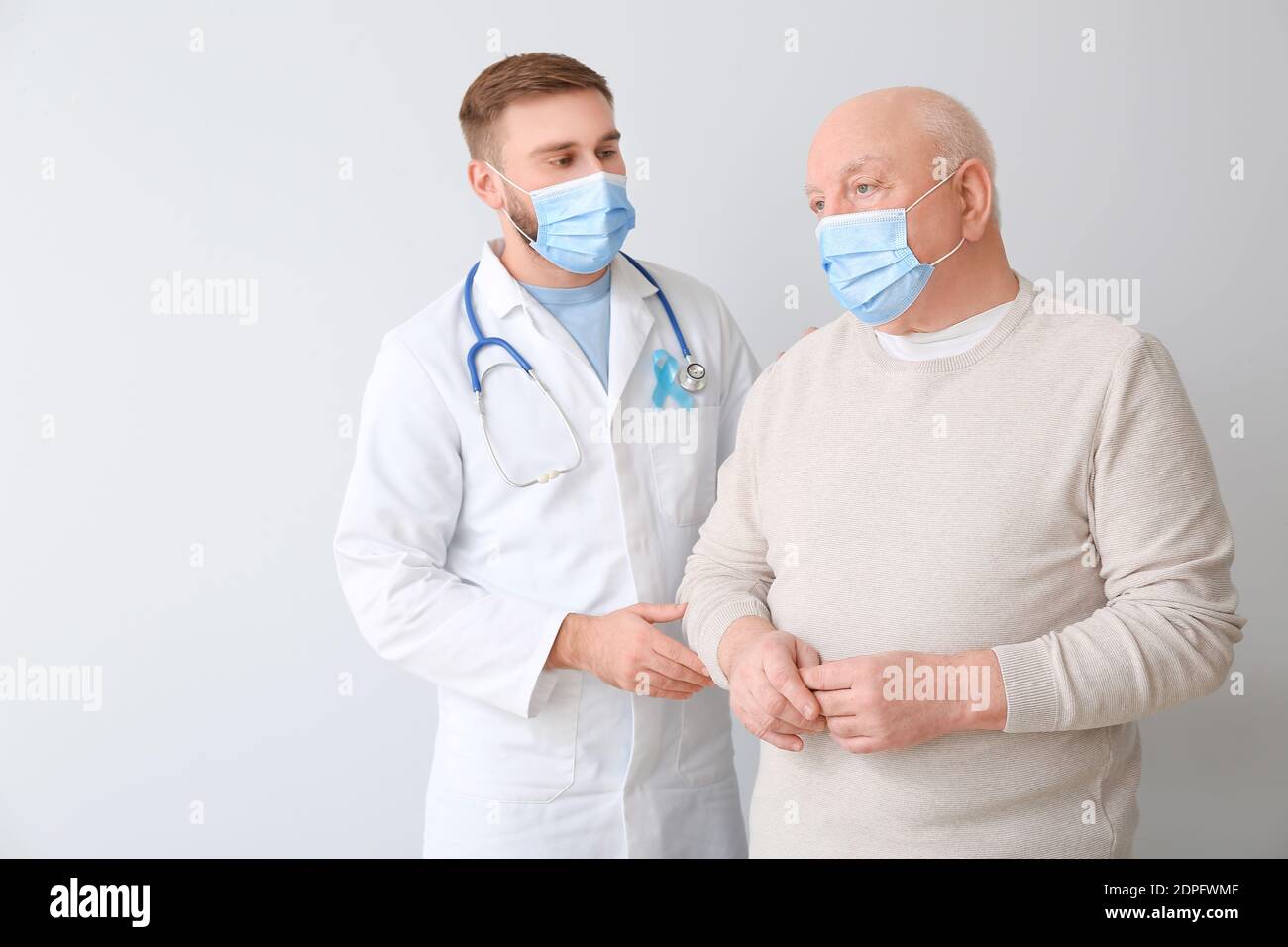 Doctor and senior man on light background. Prostate cancer awareness ...