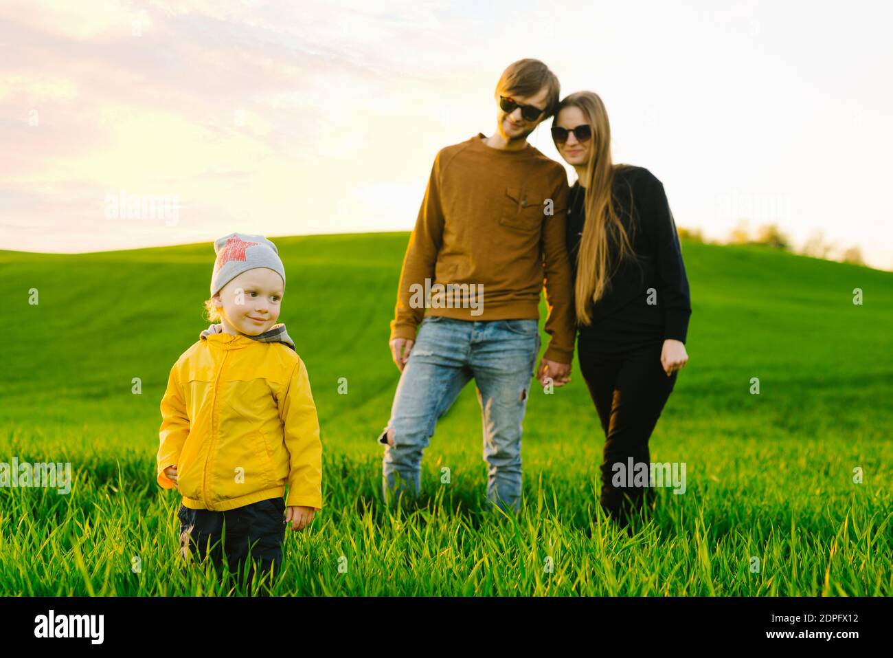 Happy family with son outdoors. Young parents walk with kid on summer ...