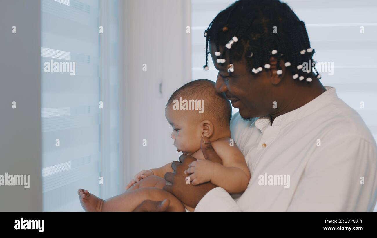 African american black father holding his mulatto baby near the window ...