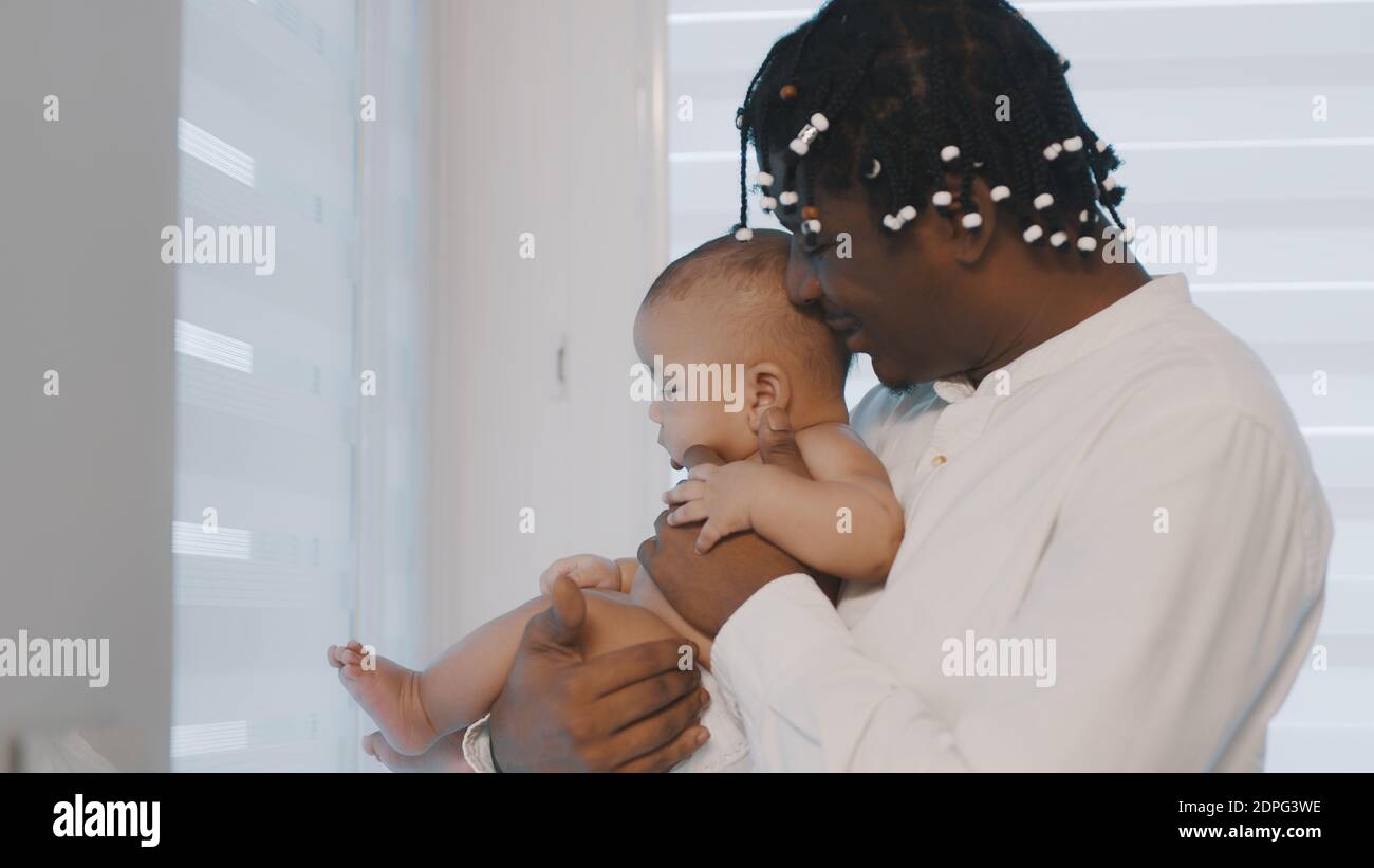 African american black father holding his mulatto baby near the window ...