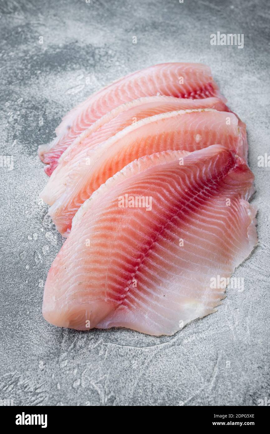 Tilapia fish fillet meat cuts, on gray background Stock Photo - Alamy