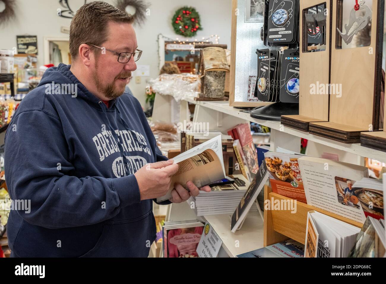 A man looking through a magazine in a store Stock Photo - Alamy