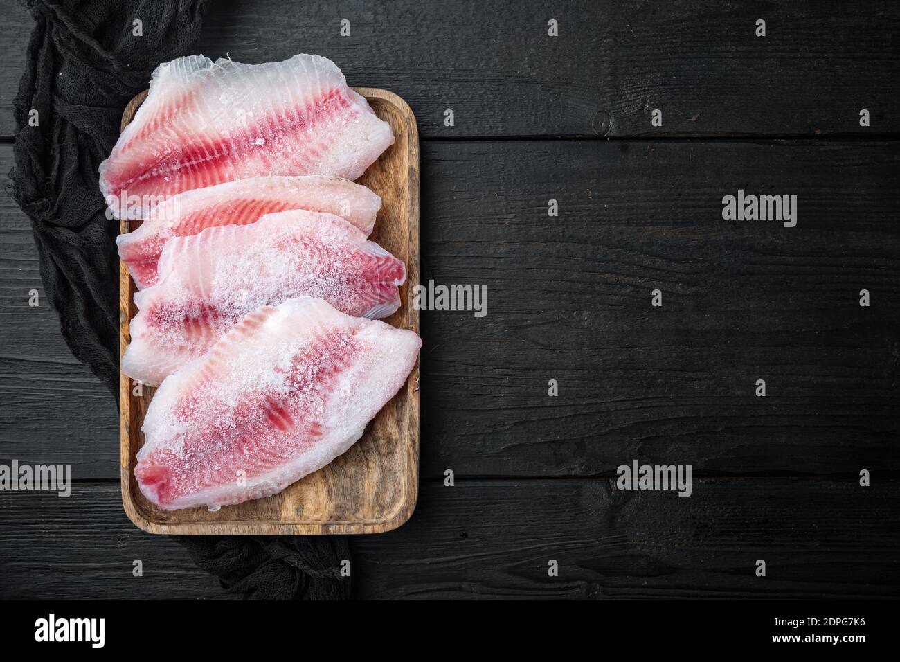 Frozen fish fillet set, on black wooden table, top view with copy space ...