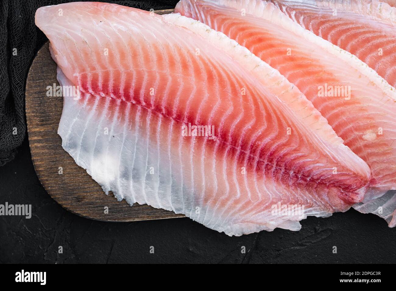 Tilapia fish fillet meat cuts, on black background, top view Stock ...