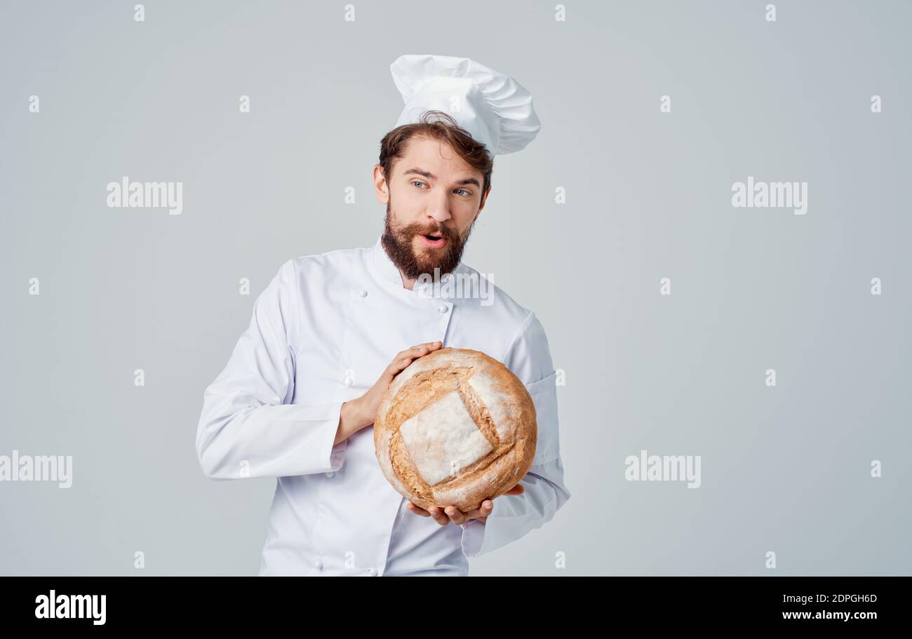 A Chef In a Light Suit and Headdress with a Round Loaf of Bread in His ...