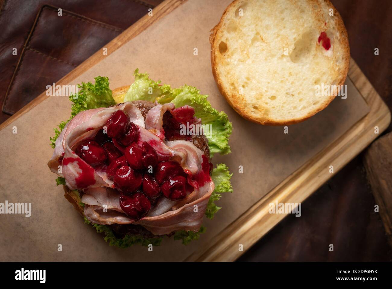 Fresh craft beef burger with fried slices of bacon and cherry sauce on ...